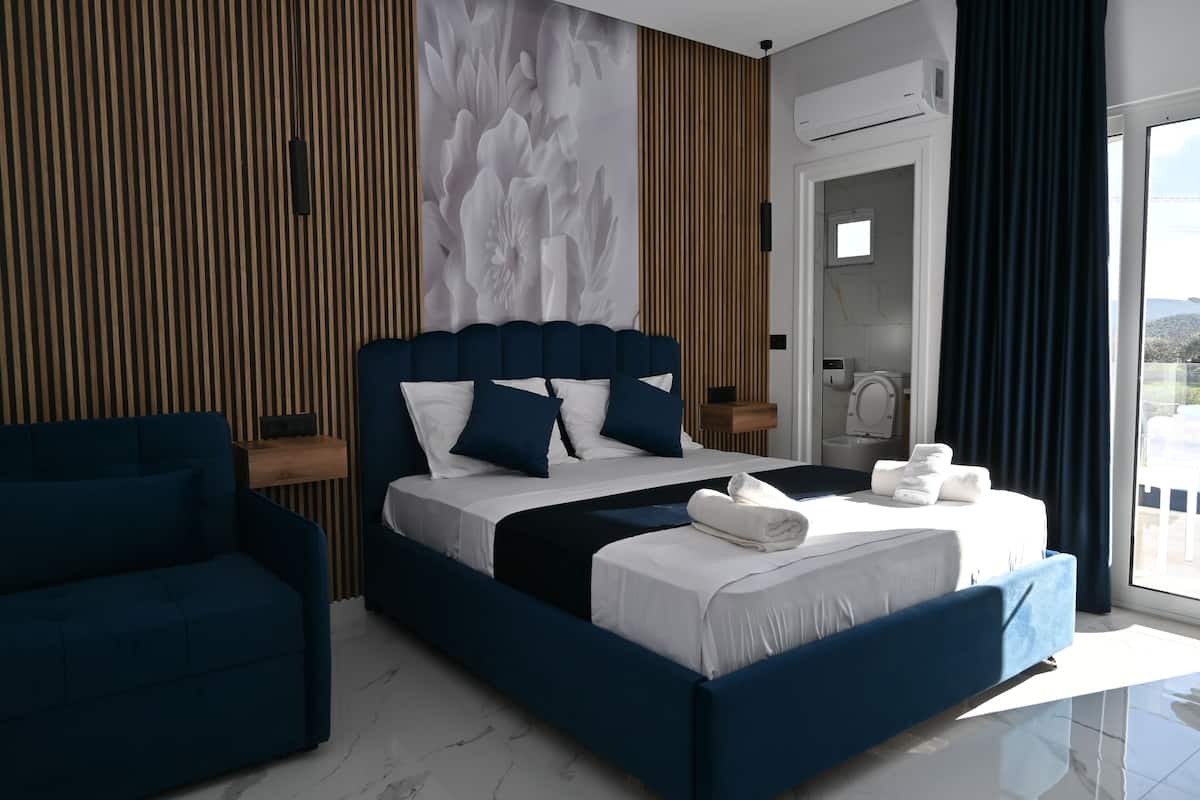 Quarto moderno com uma cama grande, um sofá azul e um painel de parede de madeira.