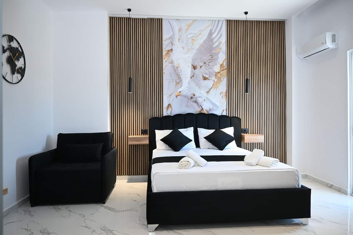 Um quarto moderno com uma cama preta e branca, uma cadeira preta e um grande mural na parede.