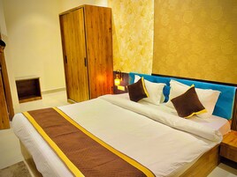Quarto de hotel com cama grande, guarda-roupa de madeira e papel de parede estampado.