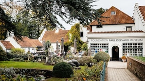 Museu Fundação Paul Delvaux com um jardim, um lago e um caminho de tijolos que leva à entrada.