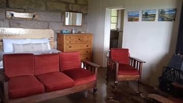 Um quarto aconchegante com cama de madeira, sofá vermelho, cômoda de madeira e lareira.