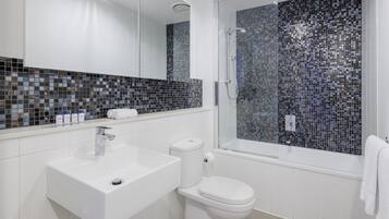 Uma casa de banho moderna com lavatório branco, sanita e chuveiro.