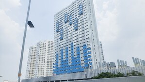 Um edifício alto com vários andares, janelas amplas e uma placa azul grande na fachada.