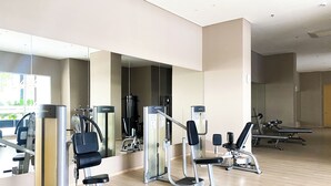 Uma academia moderna com diversos equipamentos de exercício, grandes espelhos e piso de madeira.