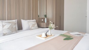 Cama bem arrumada com um tabuleiro de artigos de higiene, um vaso com flores e uma revista sobre o cobre-leito.
