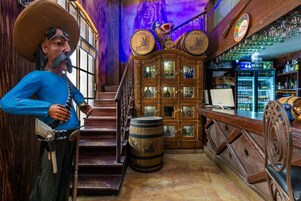 Um bar com armários de madeira, uma estátua e uma escadaria.