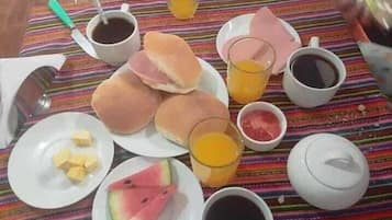 Uma mesa com alimentos, incluindo sanduíches, melancia e bebidas.