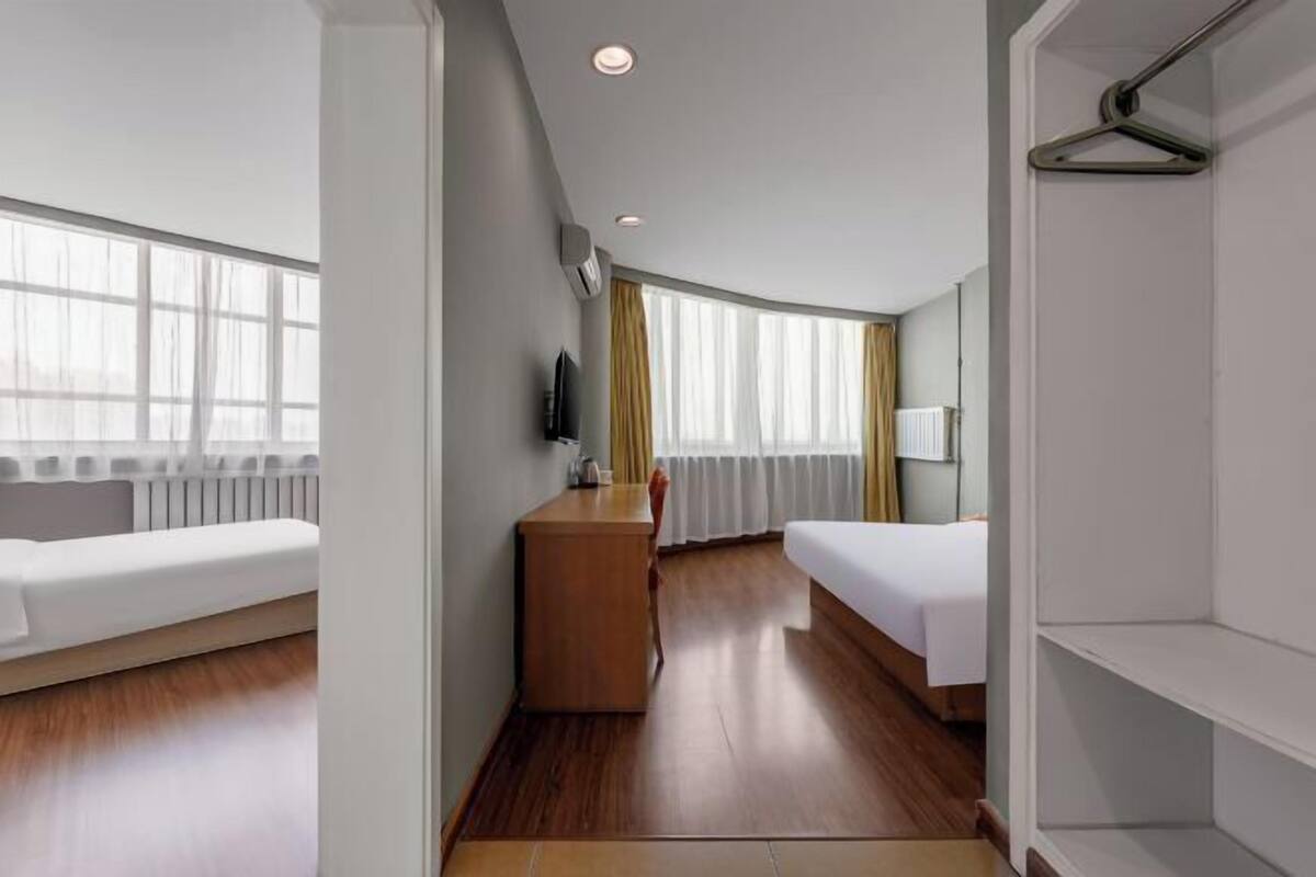 Quarto de hotel com cama, escrivaninha e televisão.