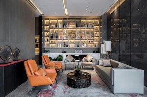Uma sala de estar moderna com sofás de couro, uma mesa de centro e uma estante repleta de livros e objetos decorativos.