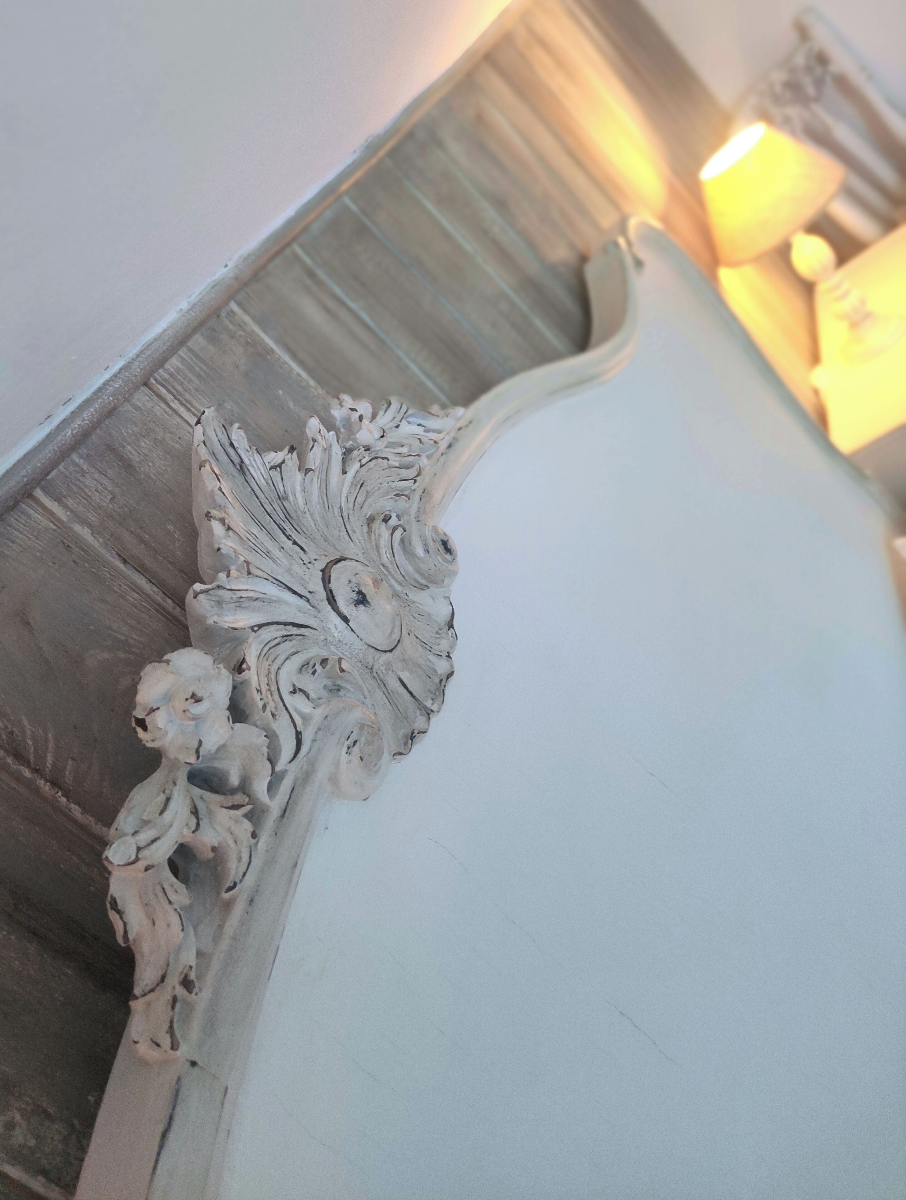Uma cadeira branca ornamentada com encosto entalhado e parede de painéis de madeira.
