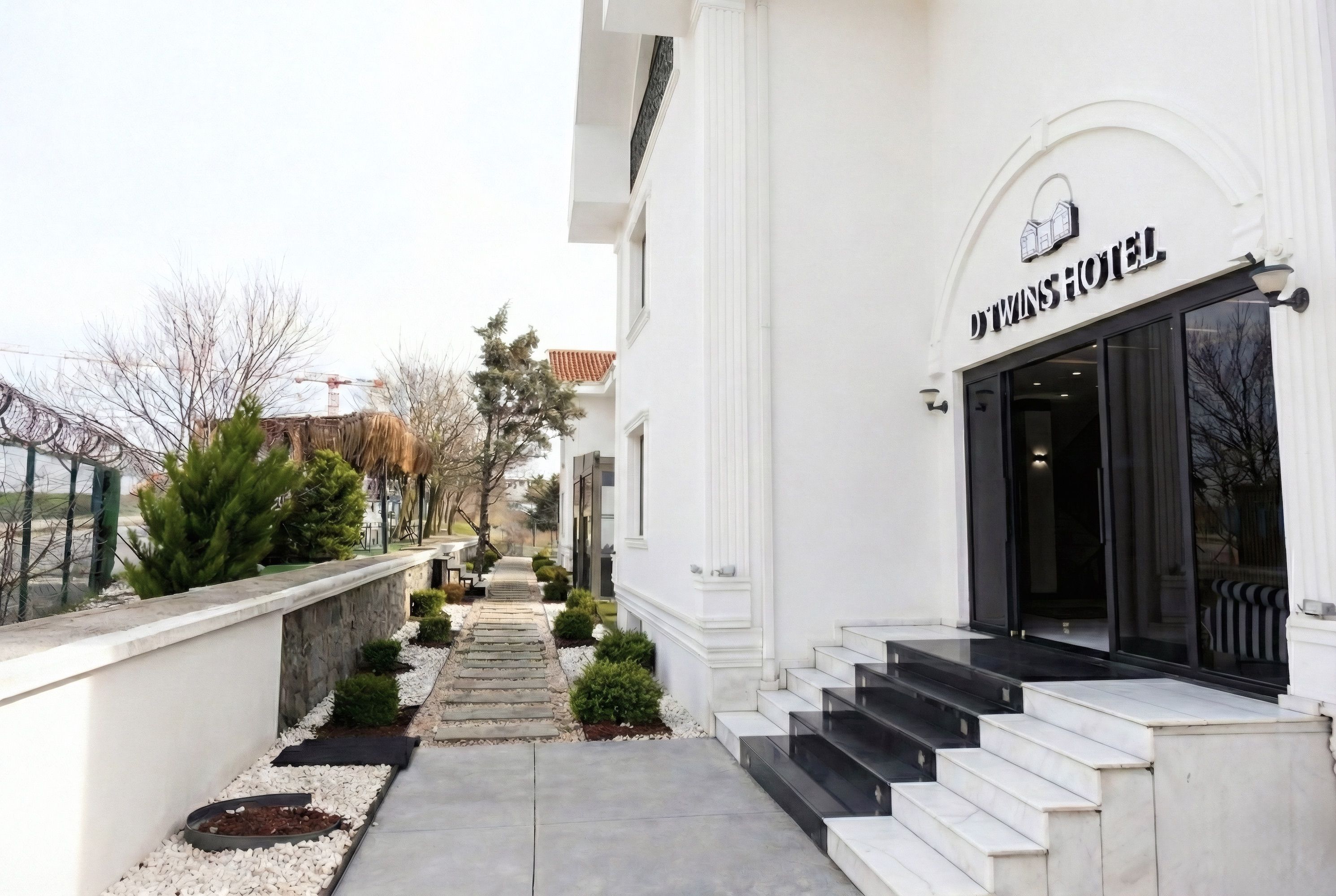 Entrada de hotel com placa, degraus e caminho que leva à porta.