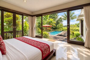 Quarto com uma cama grande, vista para uma piscina e um jardim exuberante.
