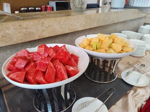 Buffet com potes de melancia e melão.