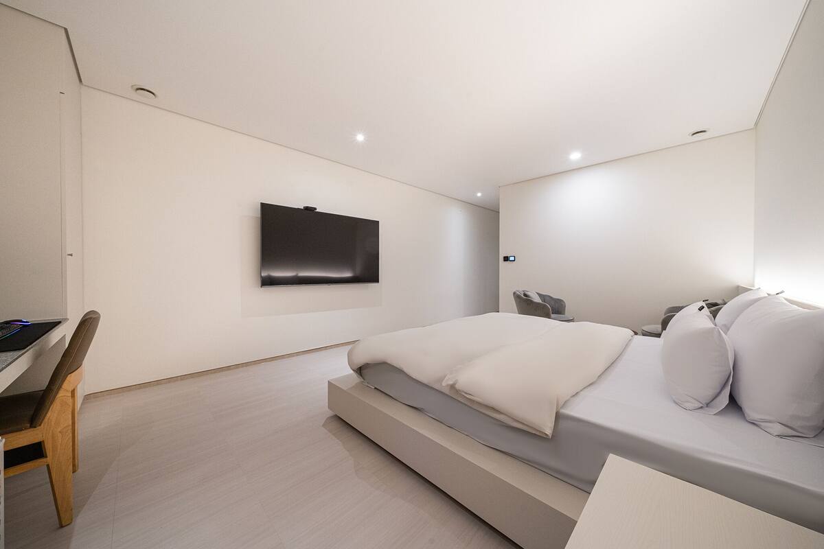 Quarto moderno com uma cama, uma escrivaninha e uma TV de tela plana na parede.