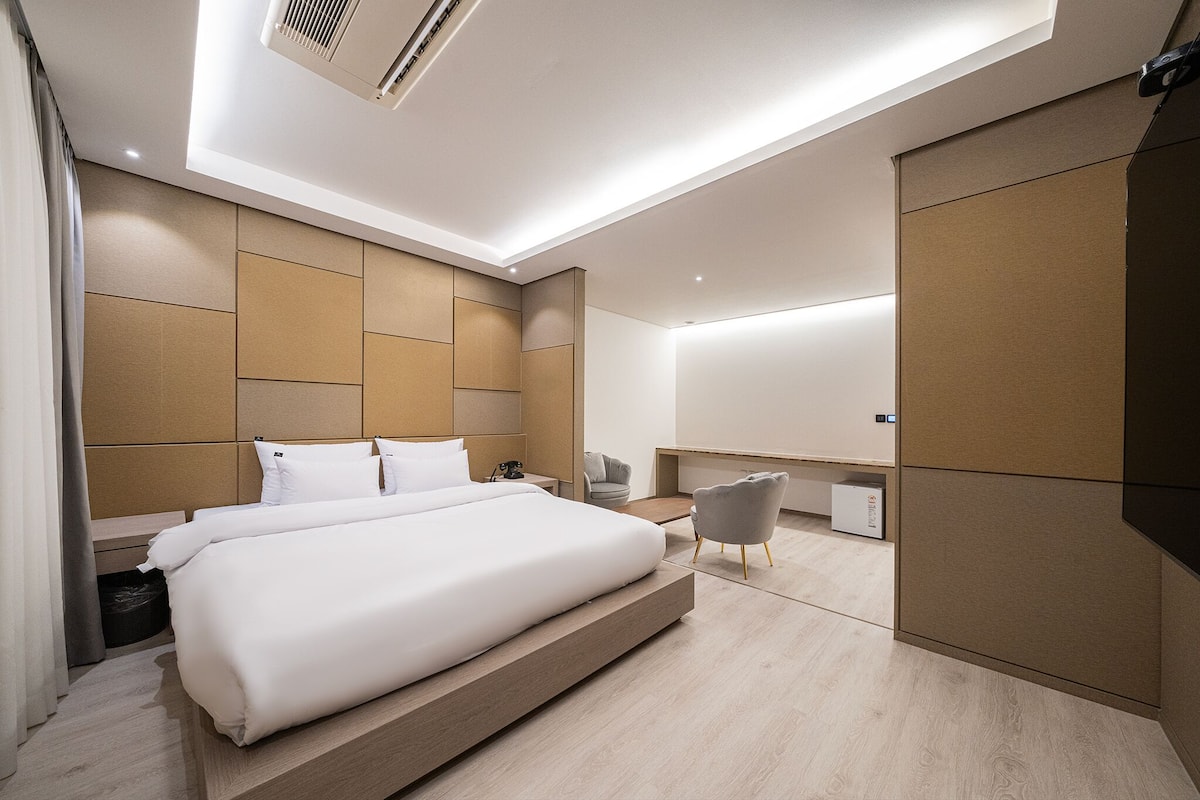 Quarto de hotel moderno com uma cama grande, uma escrivaninha e uma cadeira.
