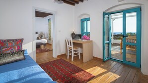 Quarto com cama, escrivaninha e vista para o exterior.