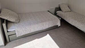 Quarto pequeno e compacto com duas camas de solteiro, cada uma com roupa de cama e almofadas estampadas.
