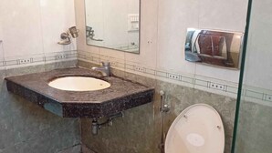 Casa de banho com lavatório de mármore, sanita e espelho.