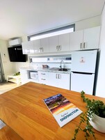 Cozinha moderna com armários brancos, forno embutido e geladeira.