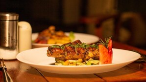 Prato de frango grelhado com legumes sobre uma mesa de madeira.