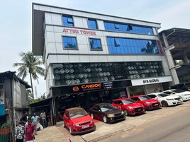 Um edifício com a placa 'ATTIRI TOWER' e uma loja 'CARDOC AUTOMOTIVE', com carros estacionados na frente.