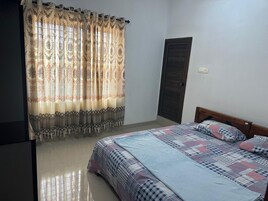Quarto com cama, cortinas e porta.