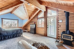 Um quarto de sótão acolhedor, com teto inclinado, uma cama, um armário e uma lareira a lenha.
