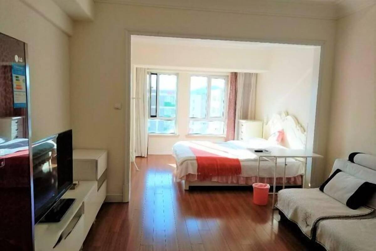 Quarto de hotel com uma cama, televisão, escrivaninha e janela com cortinas.