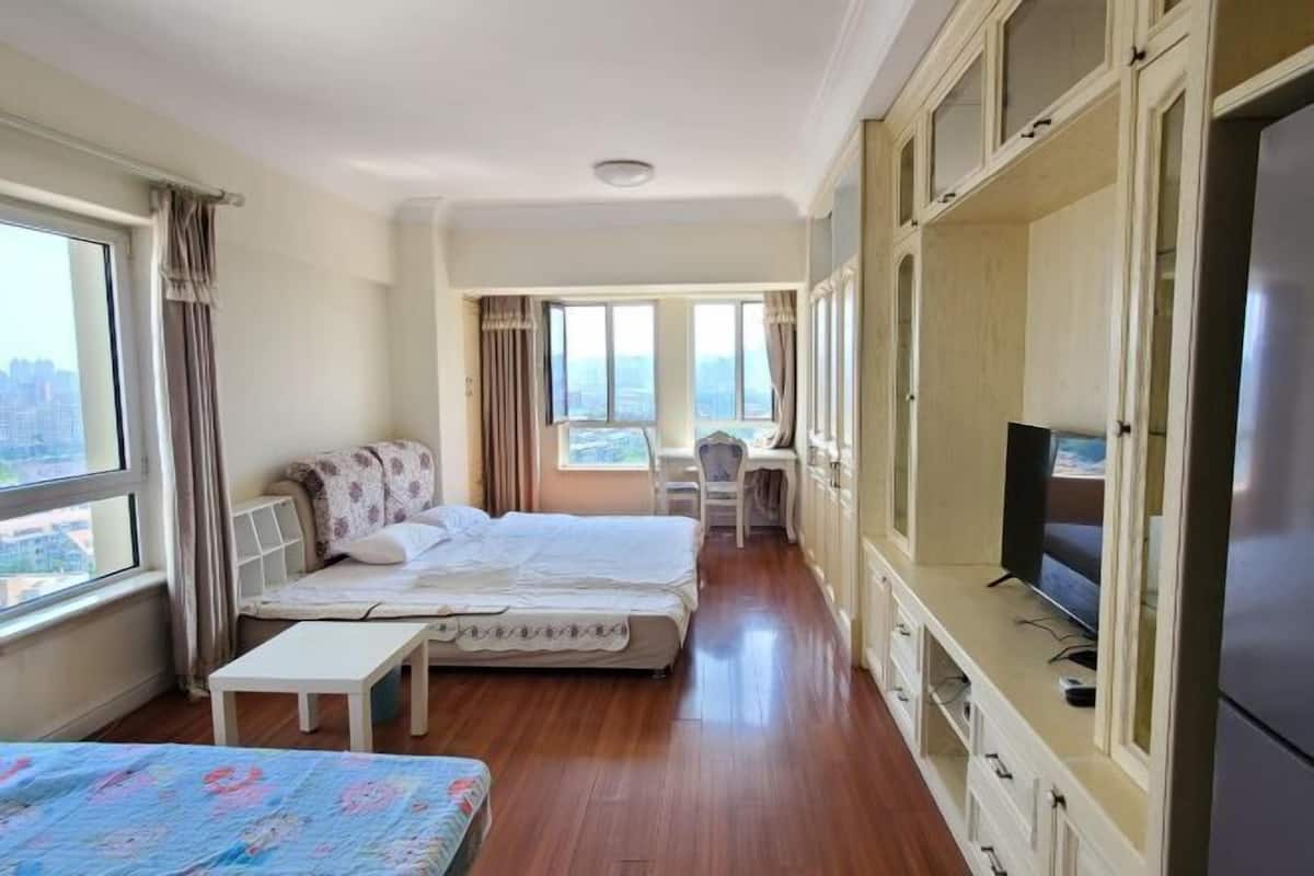 Quarto de hotel com cama, escrivaninha, televisão e vista para a cidade.