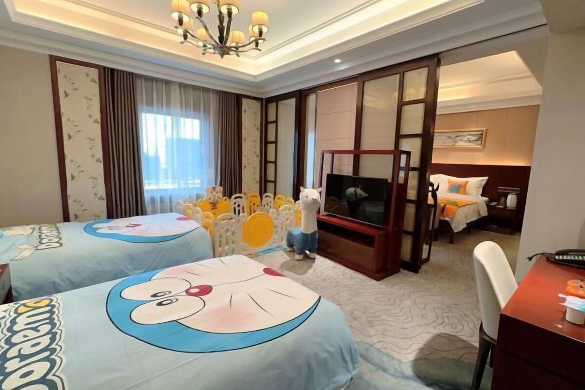 Quarto de hotel com duas camas, televisão, secretária e guarda-roupa.