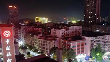 Paisagem urbana noturna com edifícios iluminados e uma placa vermelha destacada com texto branco.