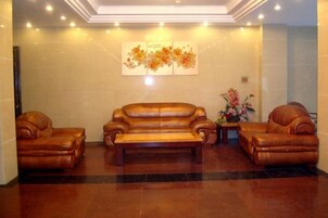 Um hall de entrada com um sofá, duas poltronas e uma mesinha com um vaso de flores.