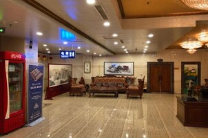 Um saguão de hotel com balcão de recepção, área de estar e máquina de venda automática.