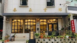Um edifício com uma placa exibindo '泰泰会馆' e uma faixa vermelha com o mesmo texto.