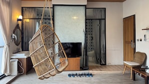 Uma sala de estar moderna com uma cadeira suspensa, uma televisão e teto de madeira.