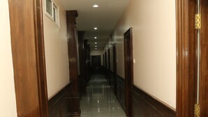 Um corredor revestido de painéis de madeira e com piso de mármore, que leva a uma porta com puxador de latão.