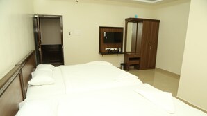 Quarto de hotel com cama, guarda-roupa, espelho e televisão.