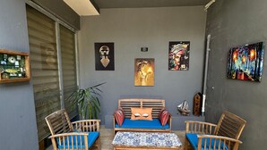 Uma área de pátio aconchegante com um banco de madeira, duas cadeiras de madeira e uma pequena mesa.