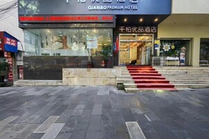 Entrada de um hotel com uma escadaria que leva à porta, uma recepção e uma placa com o nome do hotel.