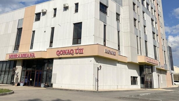 A multi-story hotel with a prominent sign reading "QONAQÜI" and "KAPAOKE" on the ground floor.