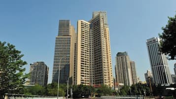 Paisagem urbana com arranha-céus, céu claro e uma rua com cerca branca.