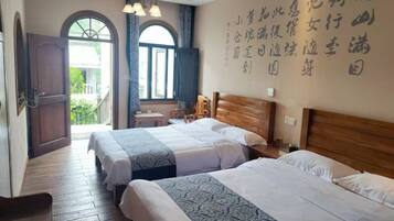 Quarto de hotel com duas camas, uma televisão, cabeceira de madeira e parede com caracteres chineses.