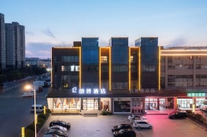 Um hotel moderno com entrada imponente, vários espaços de estacionamento e fachada bem iluminada.