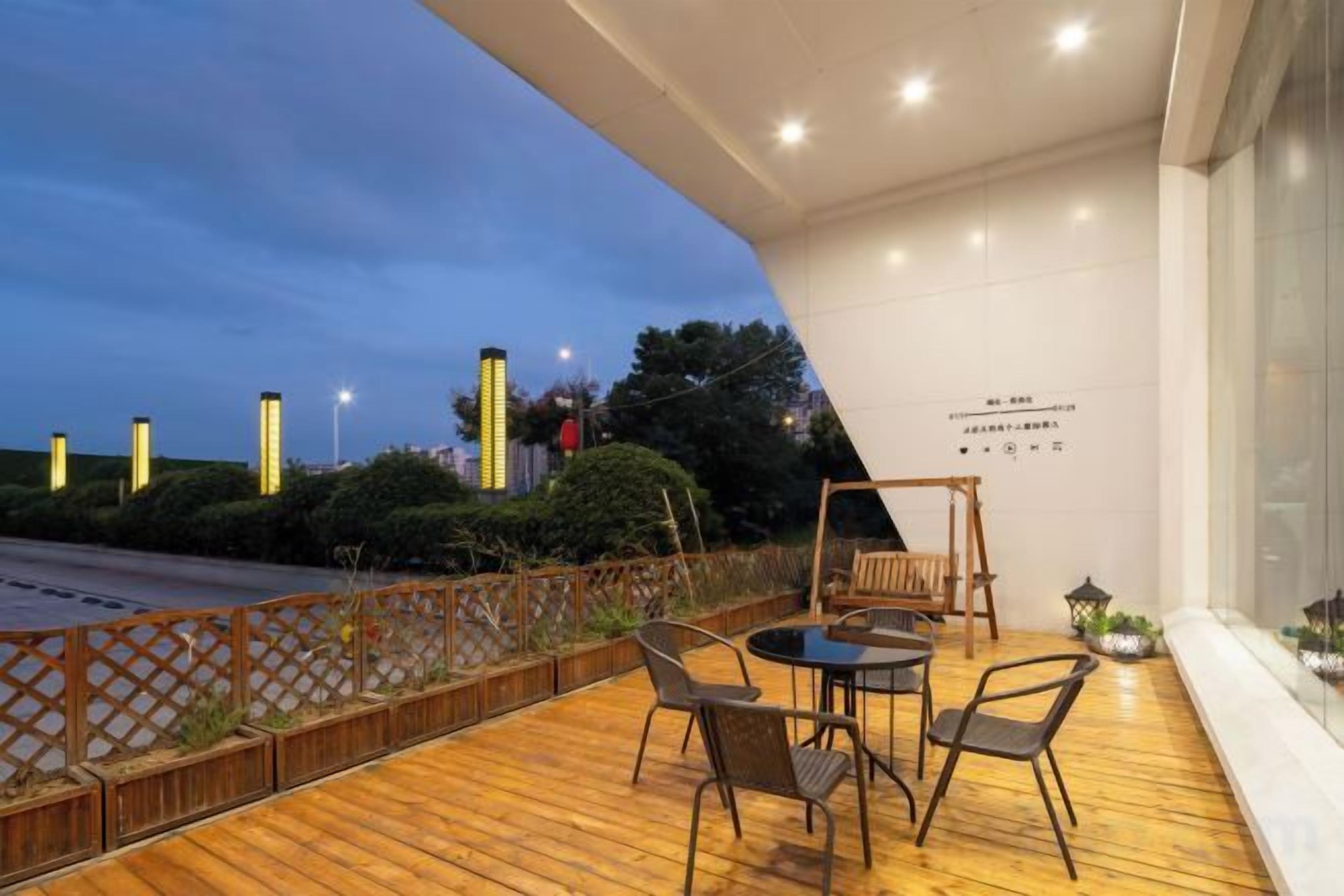 Área de estar externa com deck de madeira, cadeiras e uma mesa.