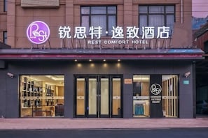 Hotel com placa, portas de vidro e interior visível com prateleiras.