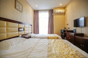 Quarto de hotel com duas camas, uma escrivaninha, uma cadeira, uma televisão e aparelho de ar condicionado.