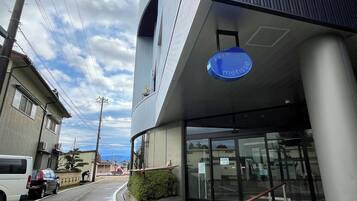 Um edifício moderno com uma grande entrada de vidro, um letreiro azul com o texto "métisse" e um céu claro.