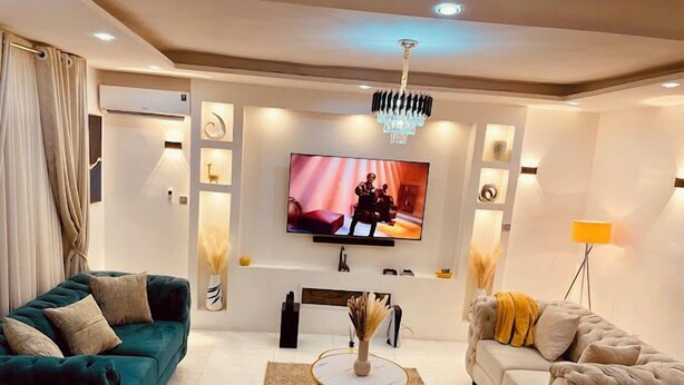 Uma sala de estar moderna com televisão de tela plana, dois sofás, uma mesa de centro e detalhes decorativos.