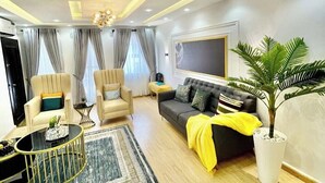 Uma sala de estar moderna com um sofá, poltronas, uma mesa de centro e uma TV.