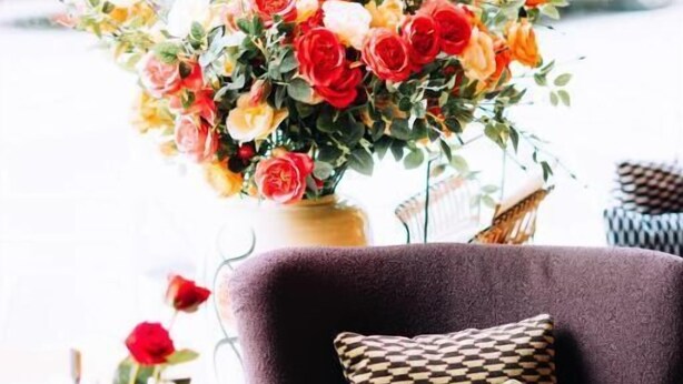 Um espaço de estar acolhedor com uma poltrona roxa, uma mesa redonda pequena e um vaso de flores.